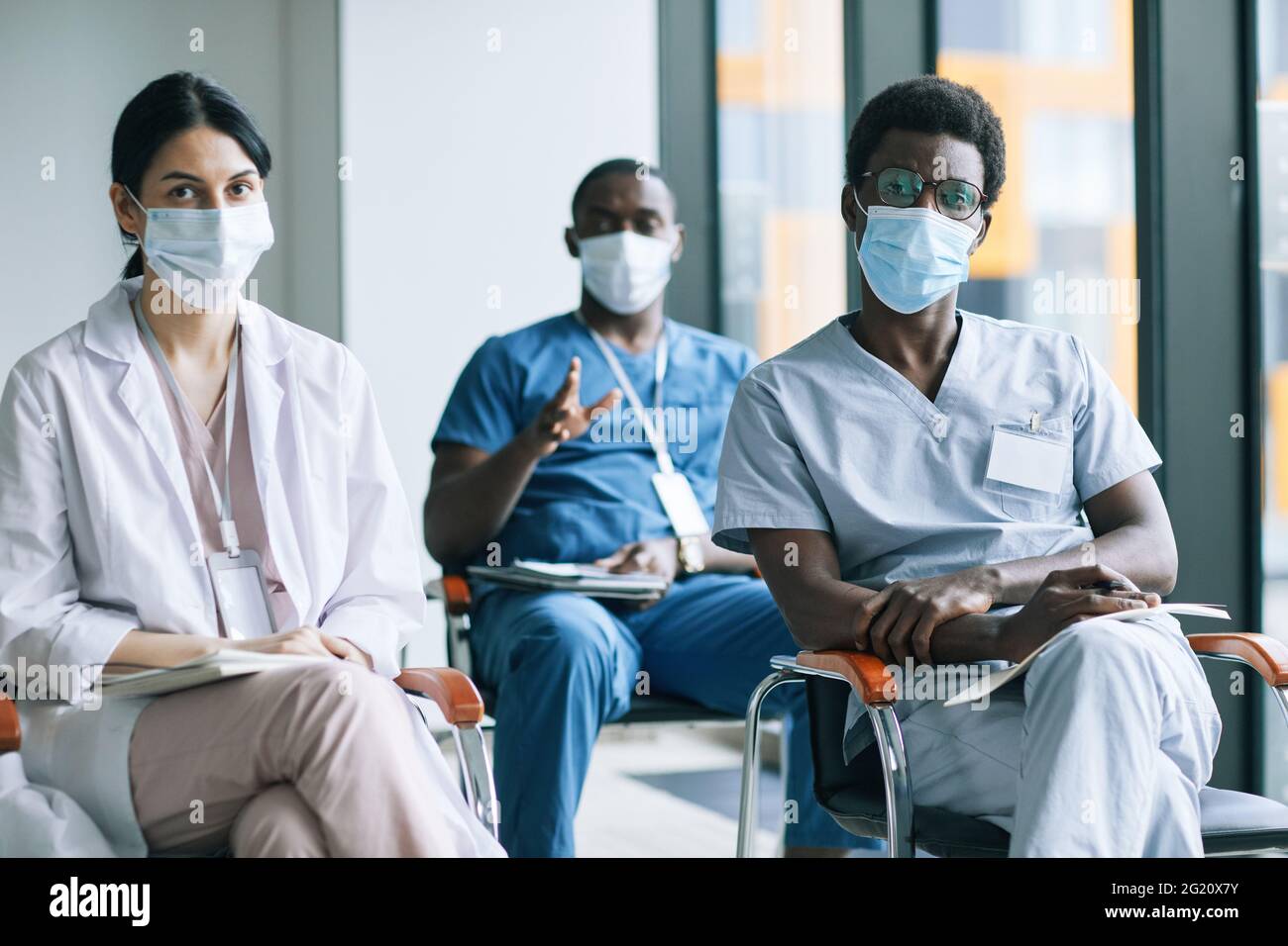 Diverse group of doctors wearing masks while attending medical ...