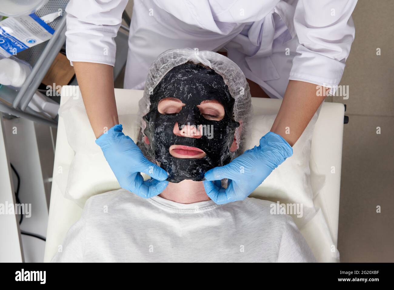 young woman with a black oxygen bubble mask on her face in beauty salon ...
