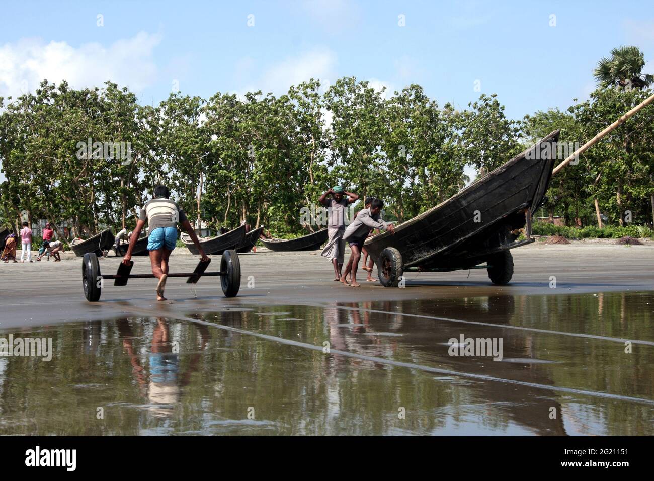 Fishermen moving their boat to the shore in Kuakata beach. Kuakata ...