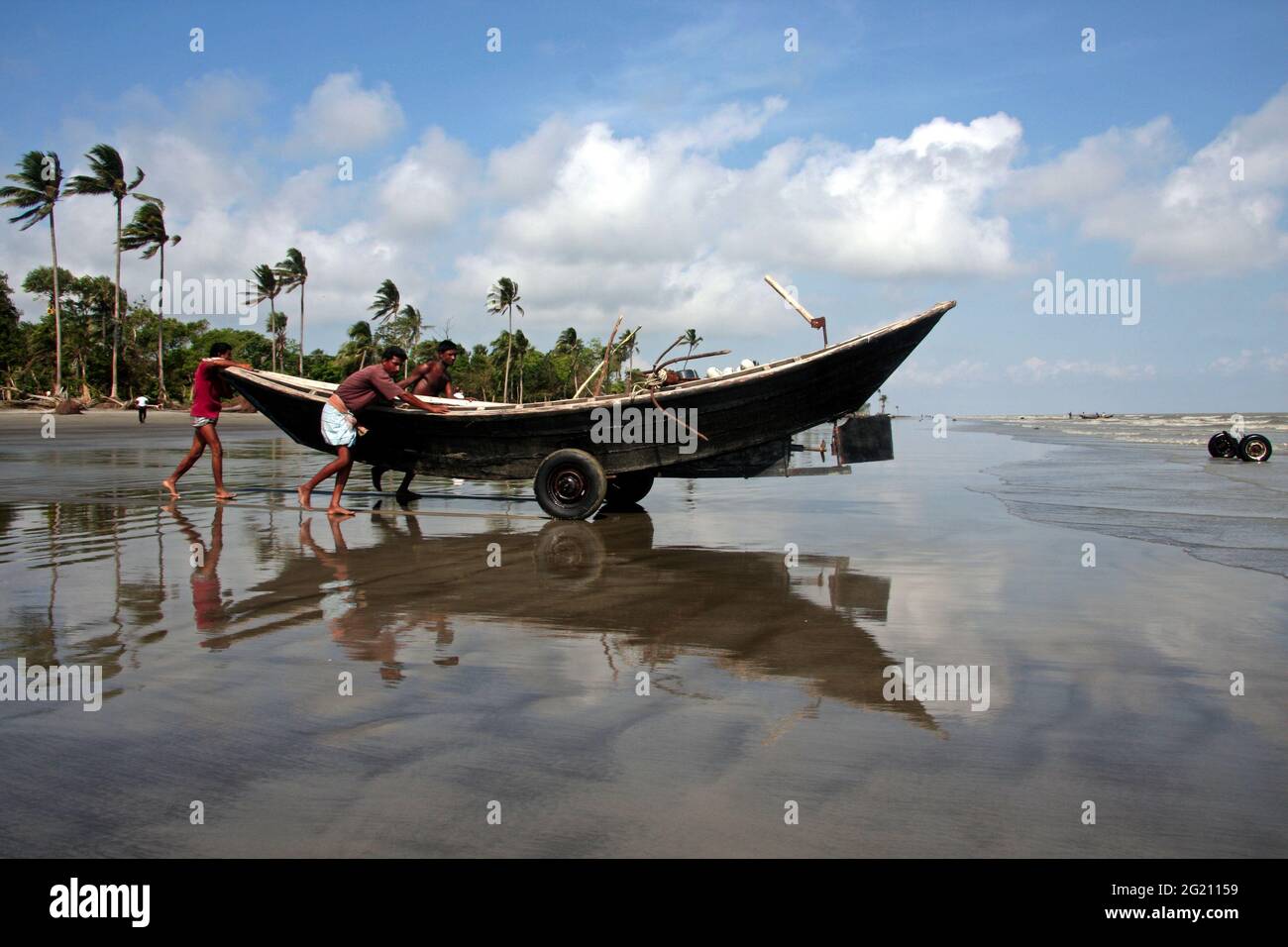 Fishermen moving their boat to the sea in Kuakata. Kuakata, locally ...