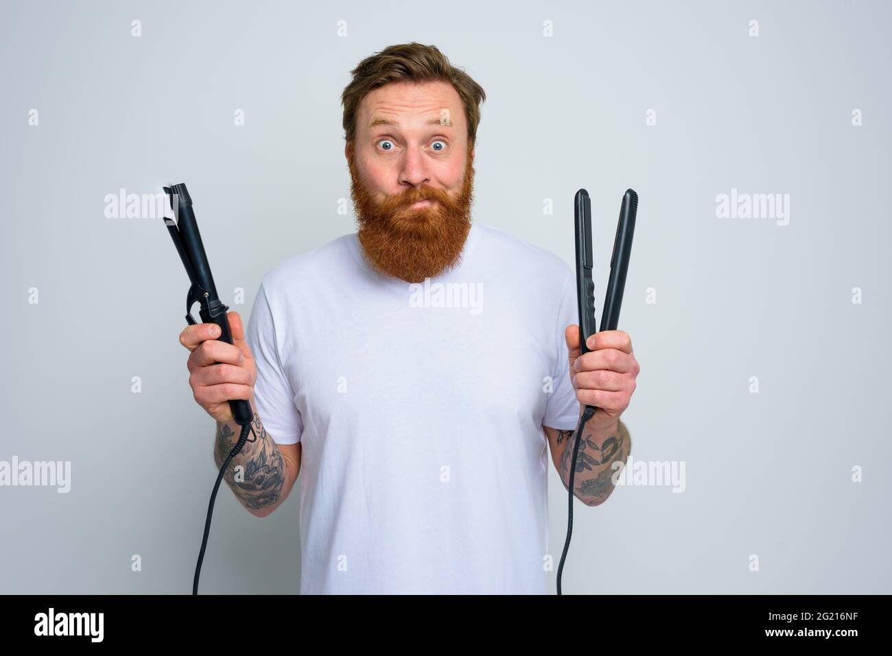 Undecided man hair with straightener is ready to work Stock Photo - Alamy