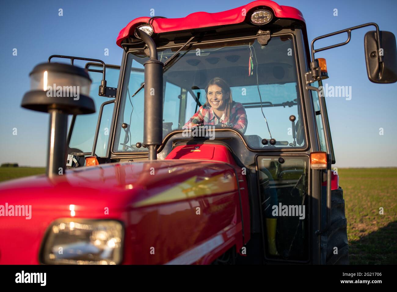 Female farmer sitting in agricultural machinery. Woman driving red ...