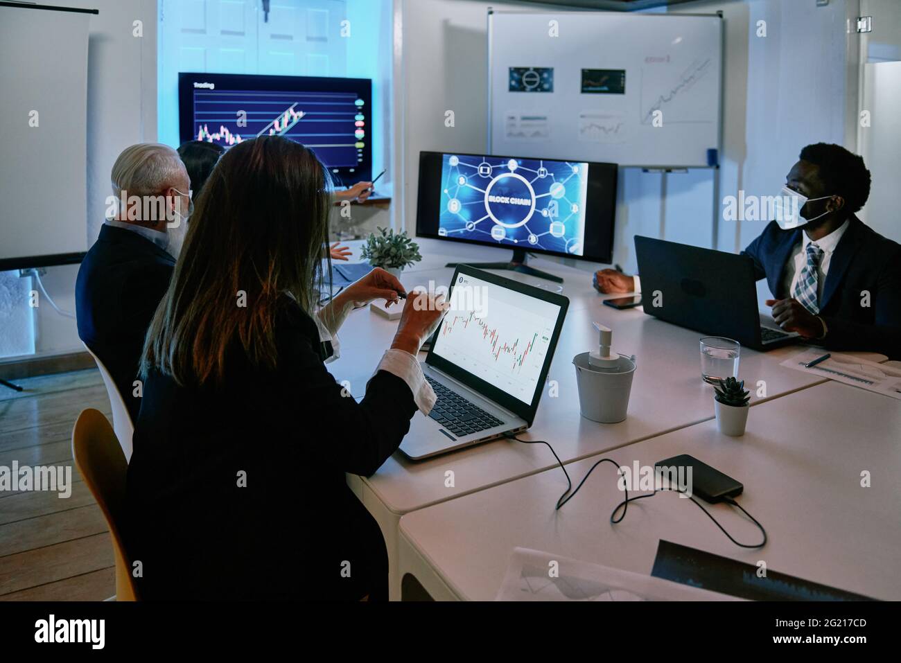 A group of people sitting at a desk with a laptop Stock Photo - Alamy