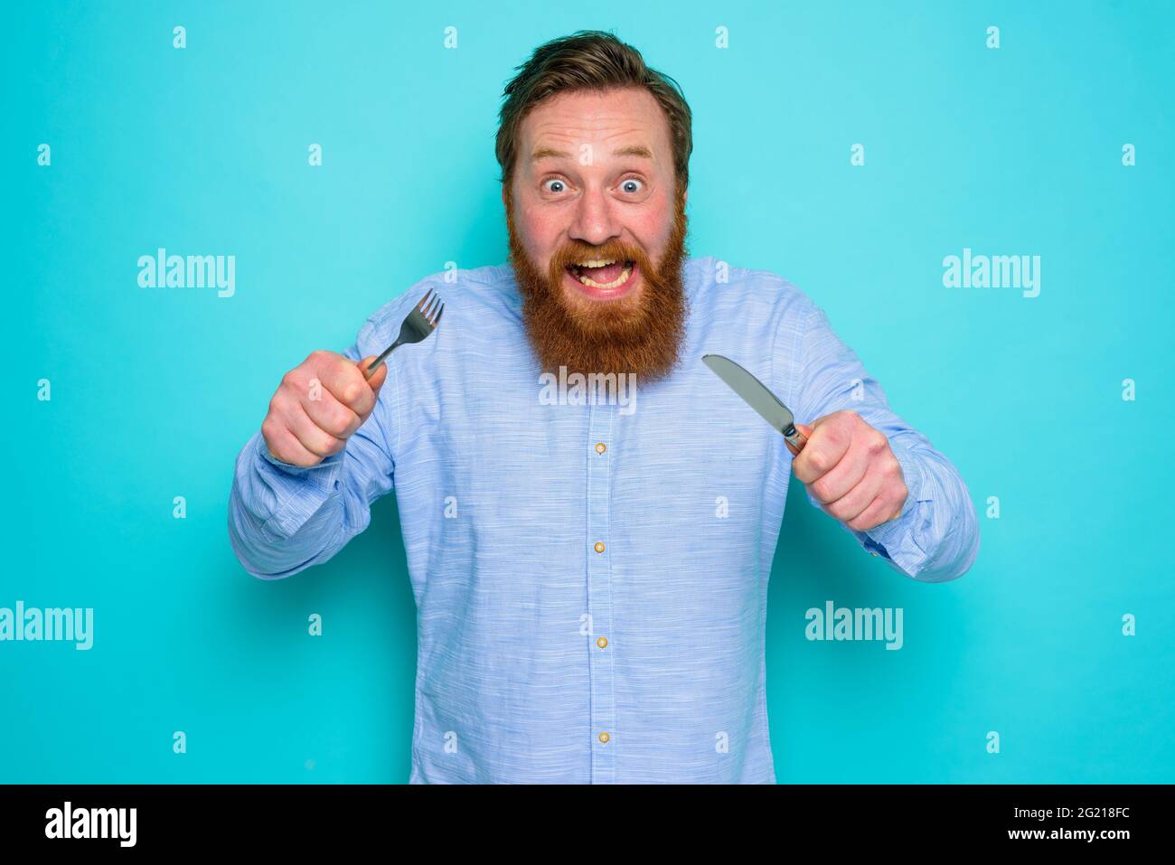 Hungry man with tattoos is ready to eat with cutlery in hand Stock ...