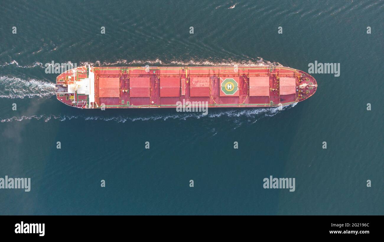 A large ocean-going cargo ship moves out to sea on calm waters. Dry ...