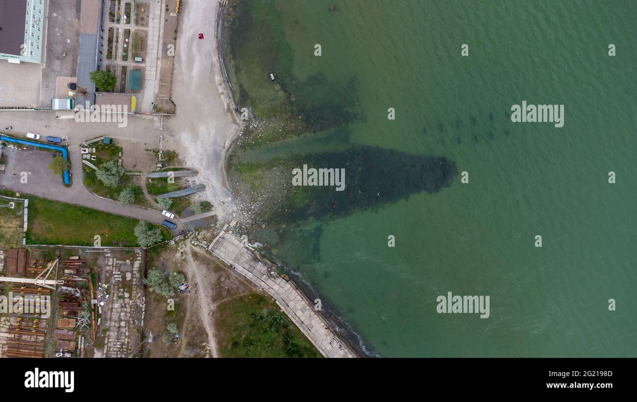 Seashore in an industrial area. Waste water discharge pipes into the ...