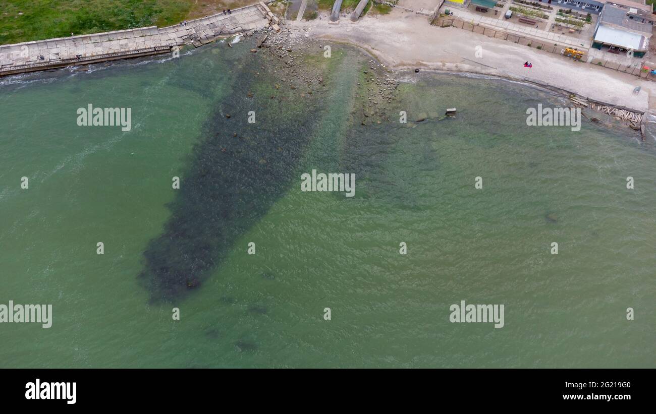 Seashore in an industrial area. Waste water discharge pipes into the ...
