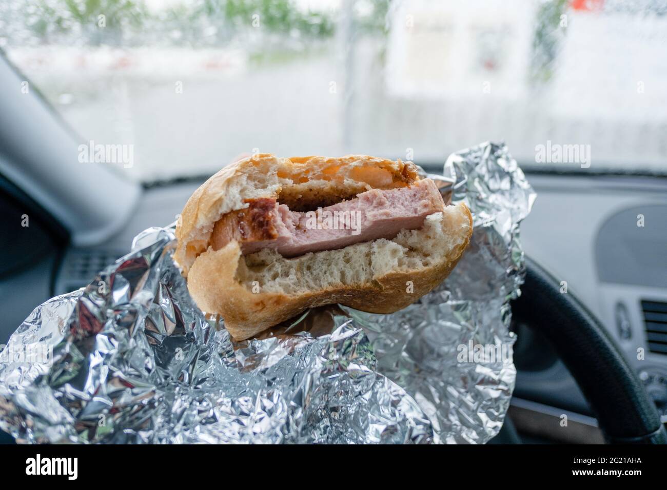 Man eating meat sandwich in car waiting in front of gate Stock Photo ...