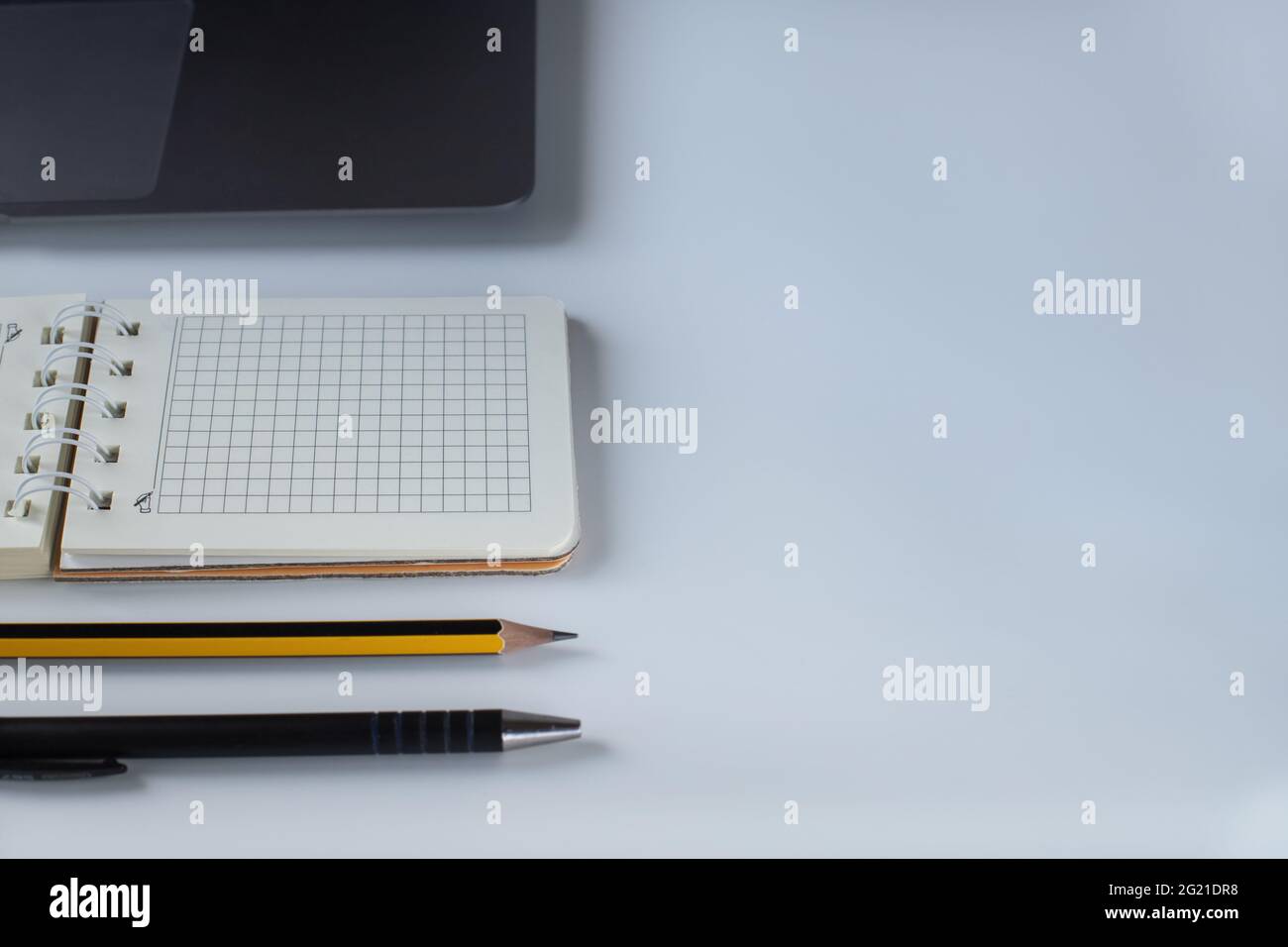 Office desk with spiral notepad, pencil and laptop on white background ...