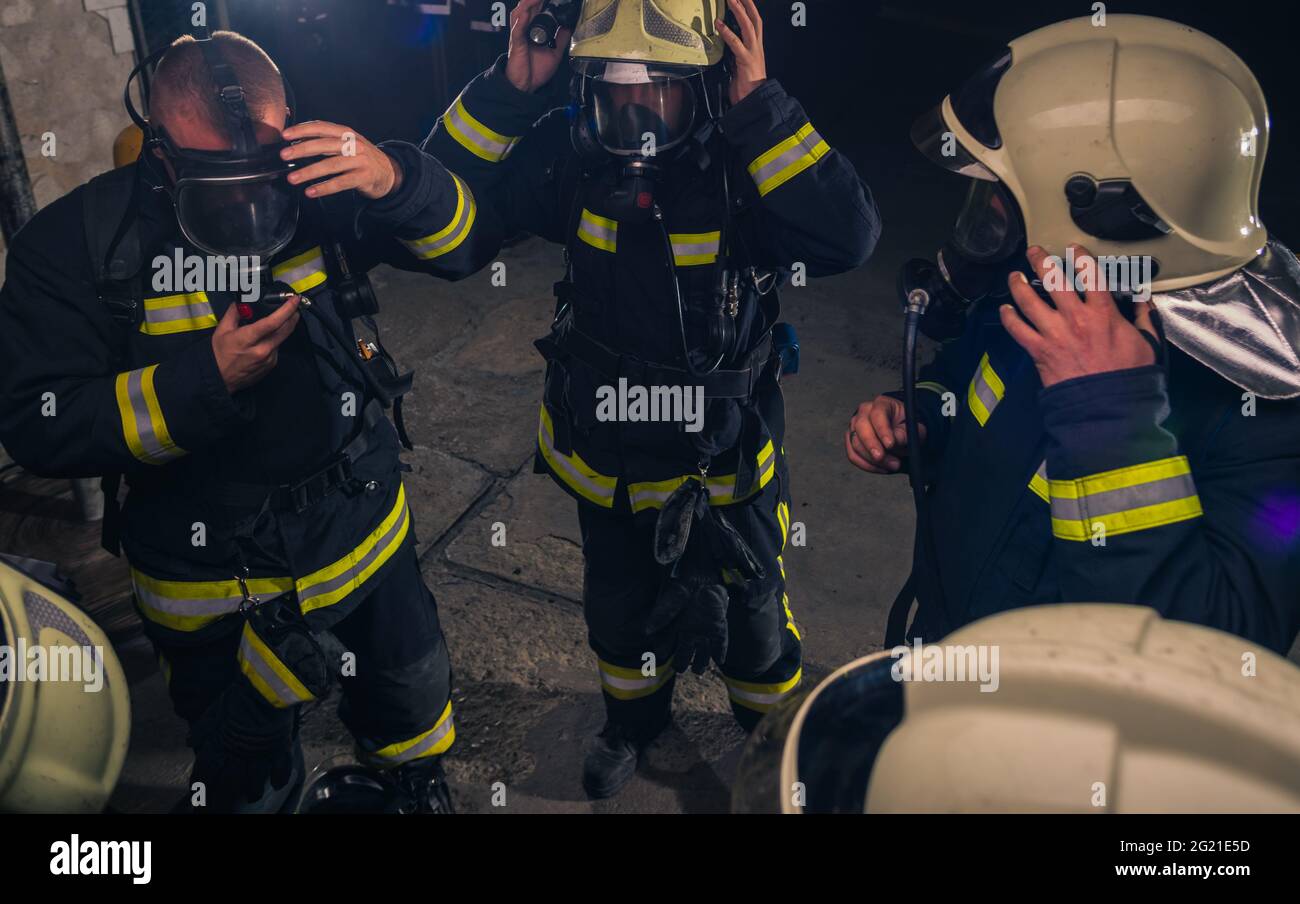 Group of firefighters standing inside the fire brigade wearing helmet ...