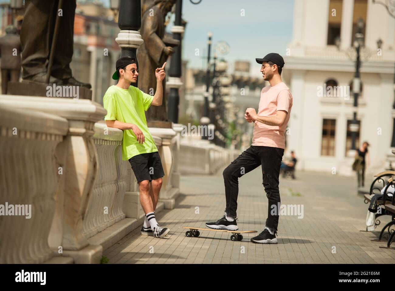 Two handsome and fit guys are having a conversation outside on a sunny ...