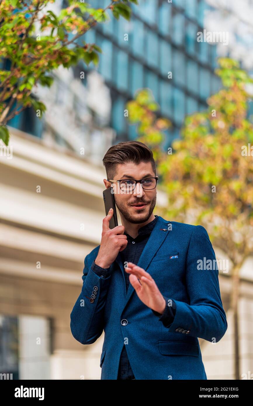 Confident businessman talking on cellphone while posing on the bridge Stock Photo - Alamy