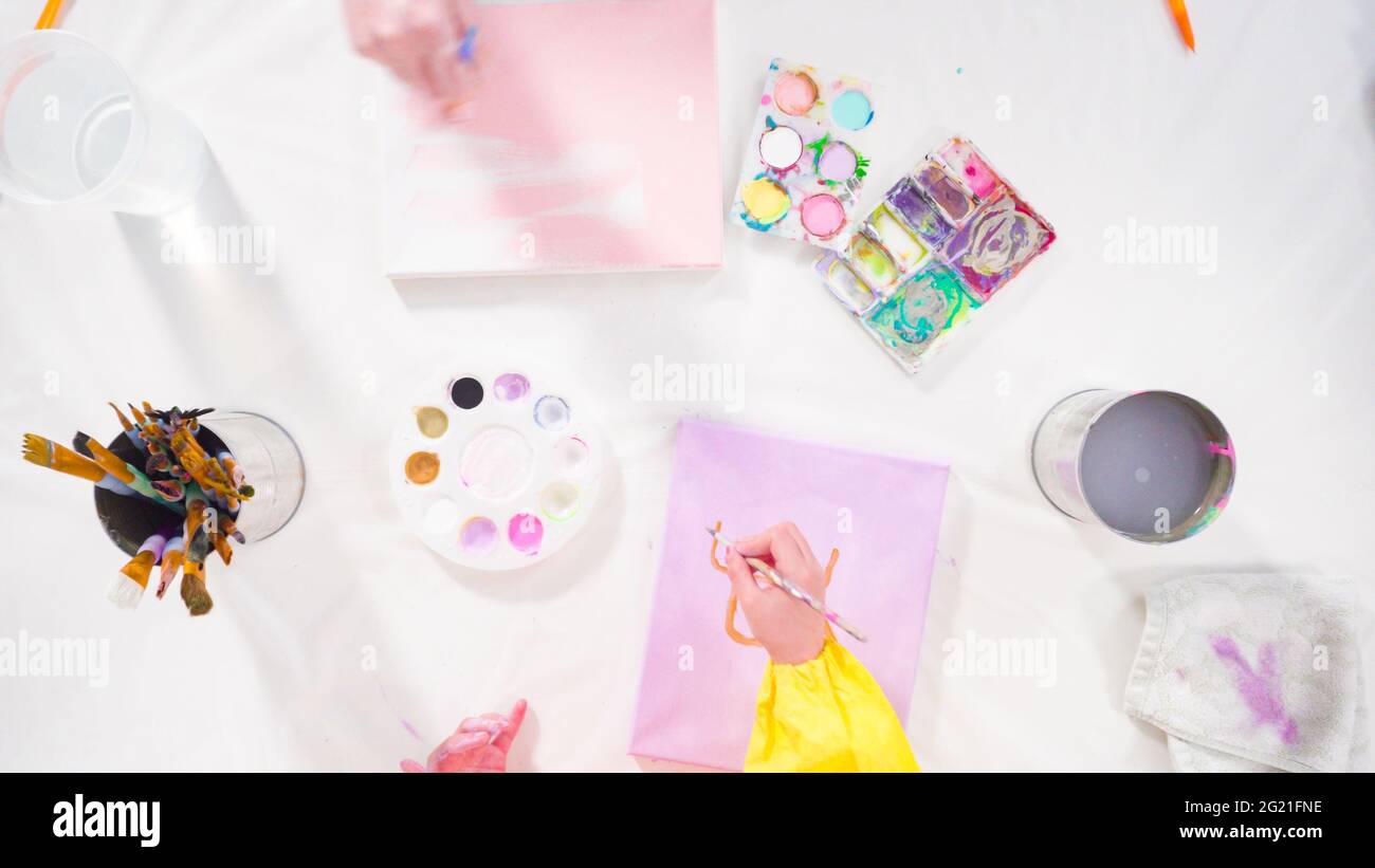 Flat lay. Little girl painting with acrylic paint on canvas with her ...