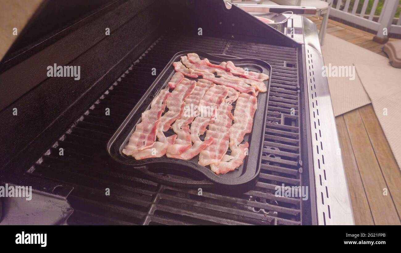 Cooking bacon stips on an outdoor gas grill Stock Photo - Alamy