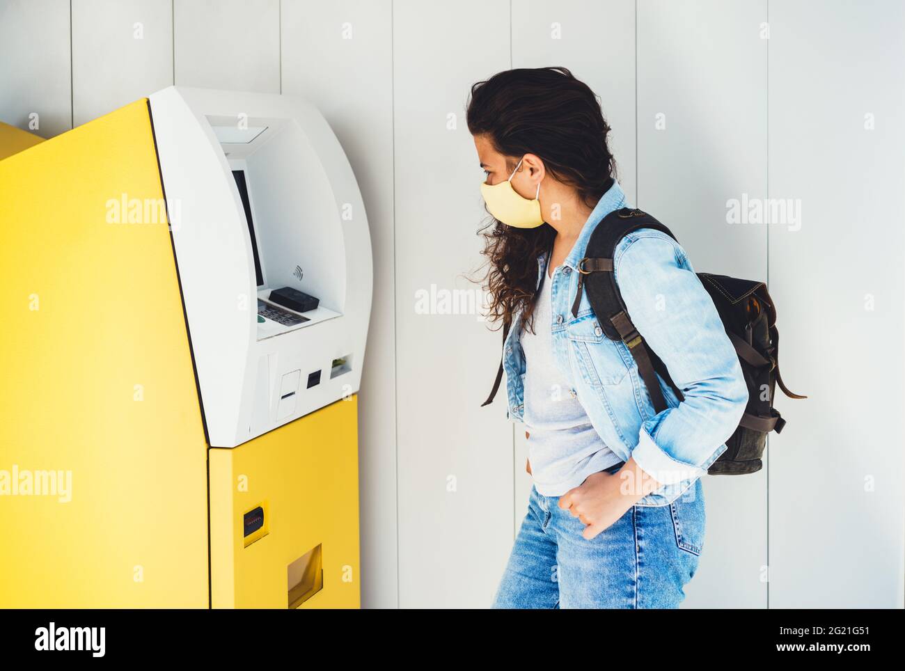 Pretty young woman traveler wearing protective face mask withdrawing ...