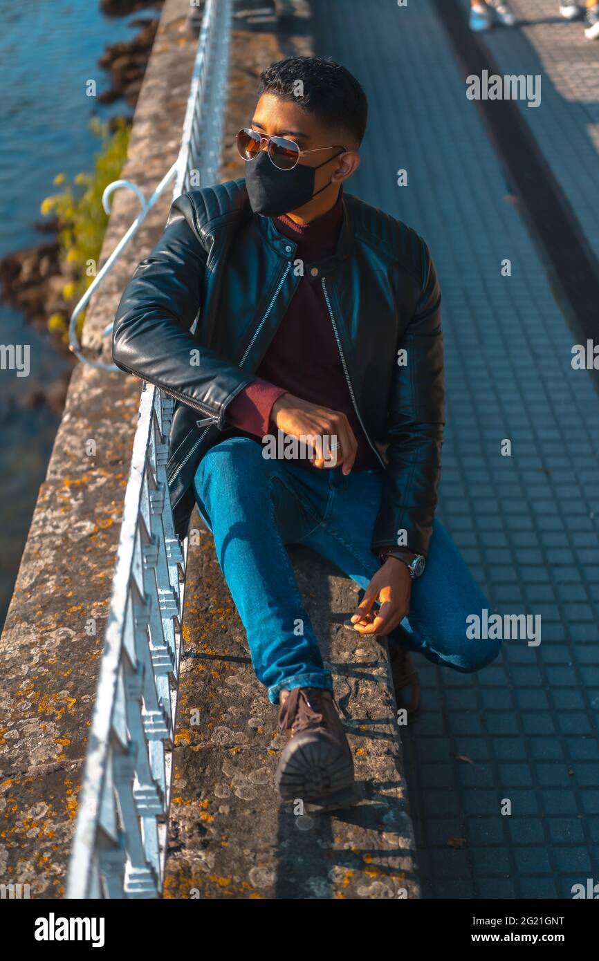 Vertical shot of a Hispanic male posing in a city in a face mask Stock ...