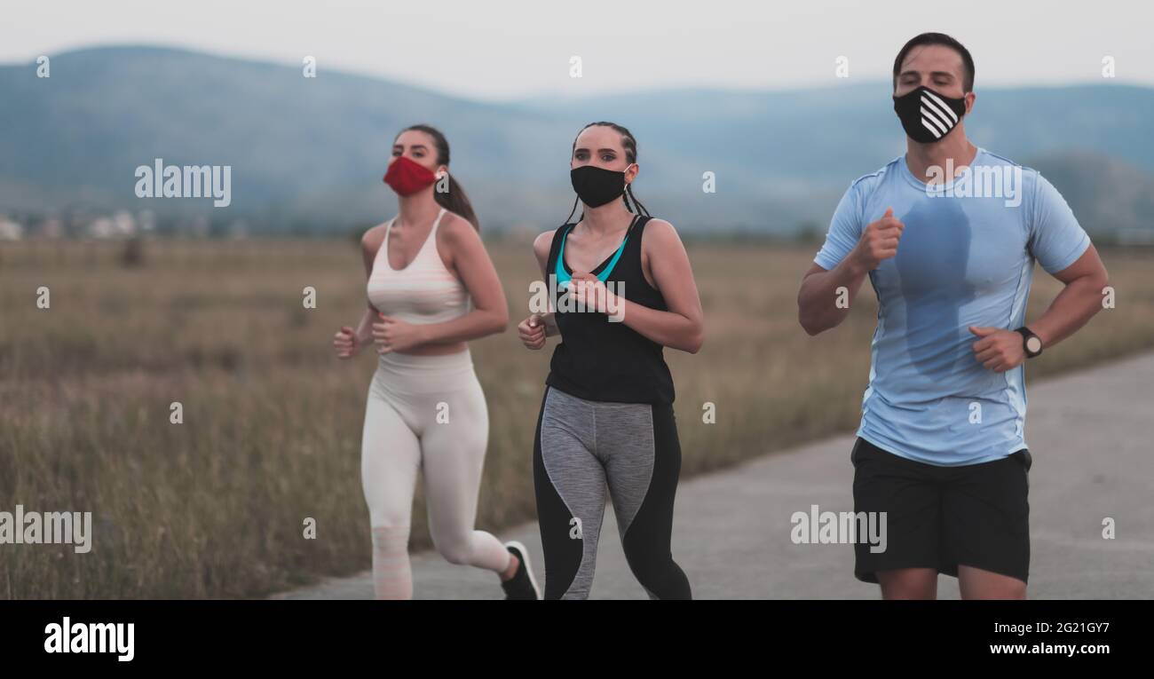 Three multiethnic women runners group wear face masks running keep ...