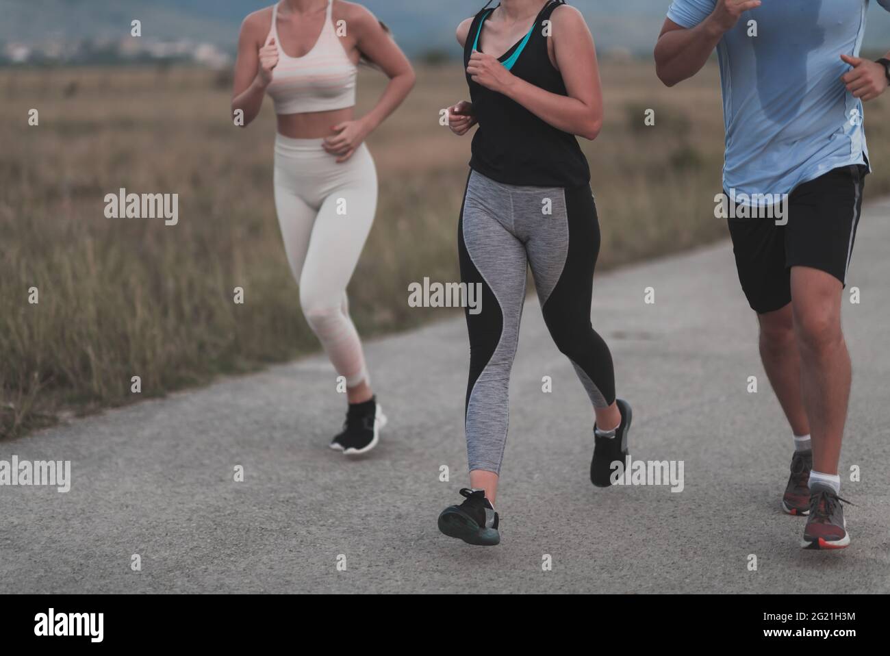 Three multiethnic women runners group wear face masks running keep ...