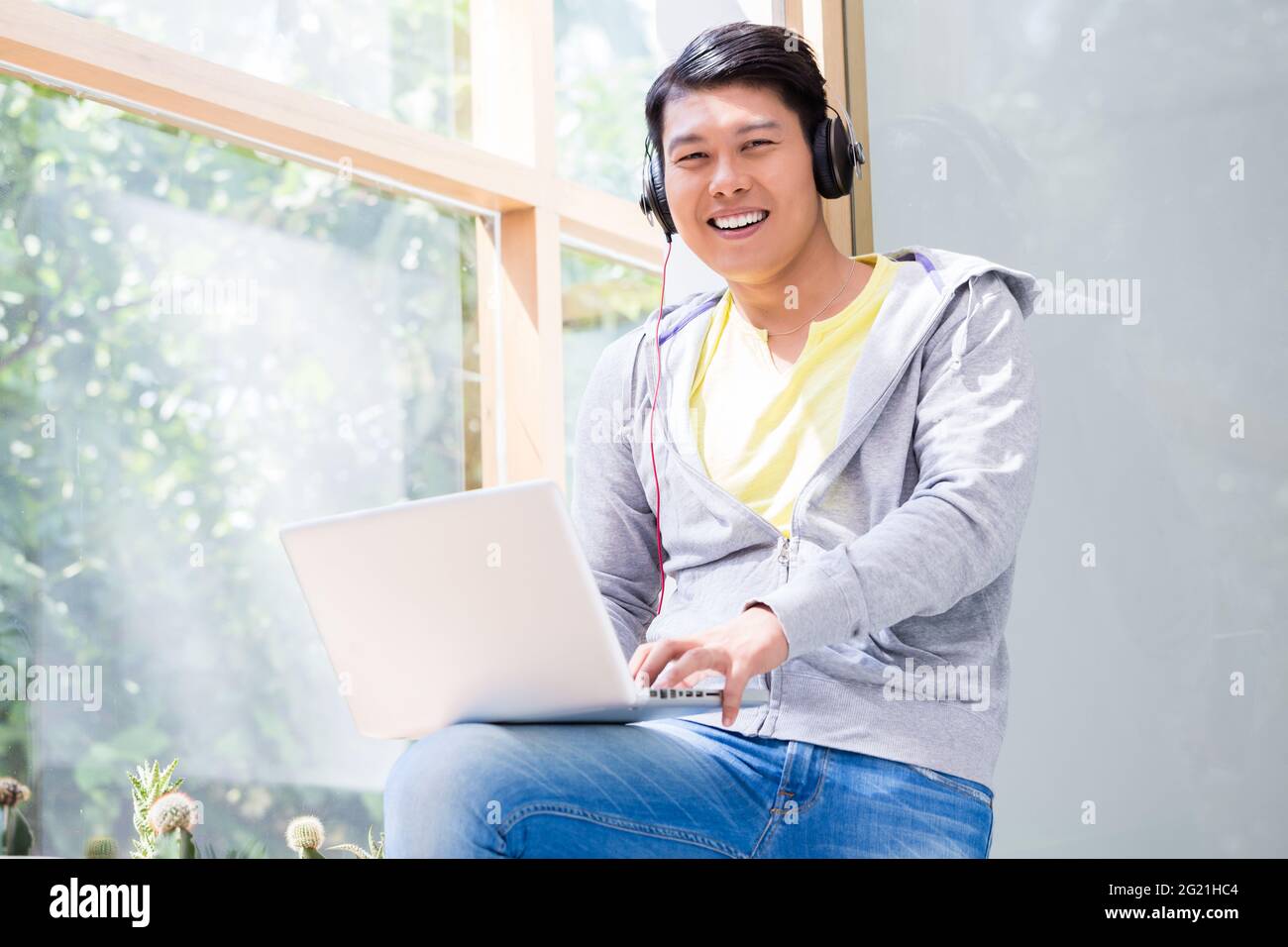 Portrait of Chinese young man wearing casual clothes while using a ...