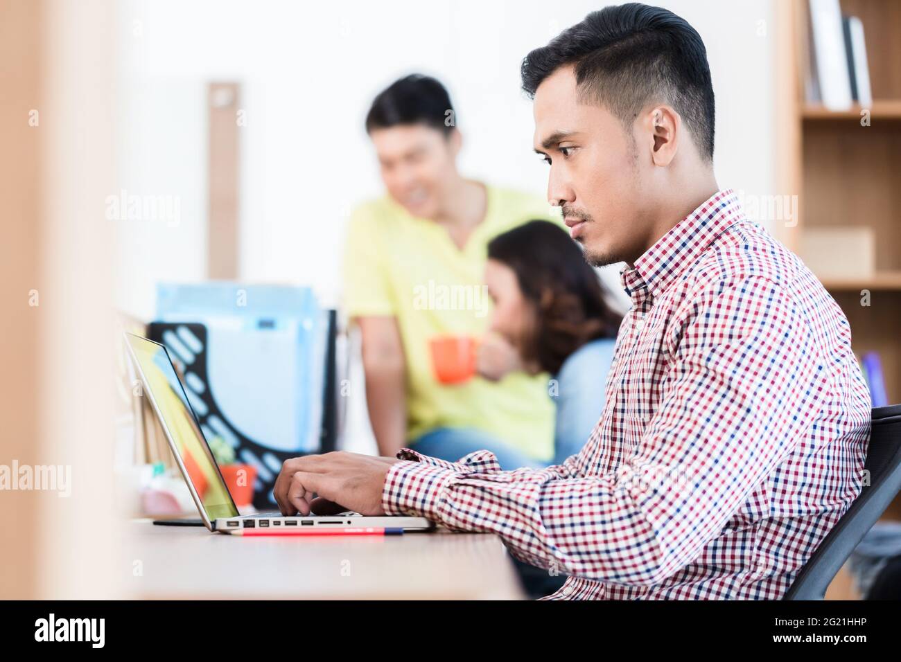 Side view portrait of a young dedicated Asian expert sitting at his ...