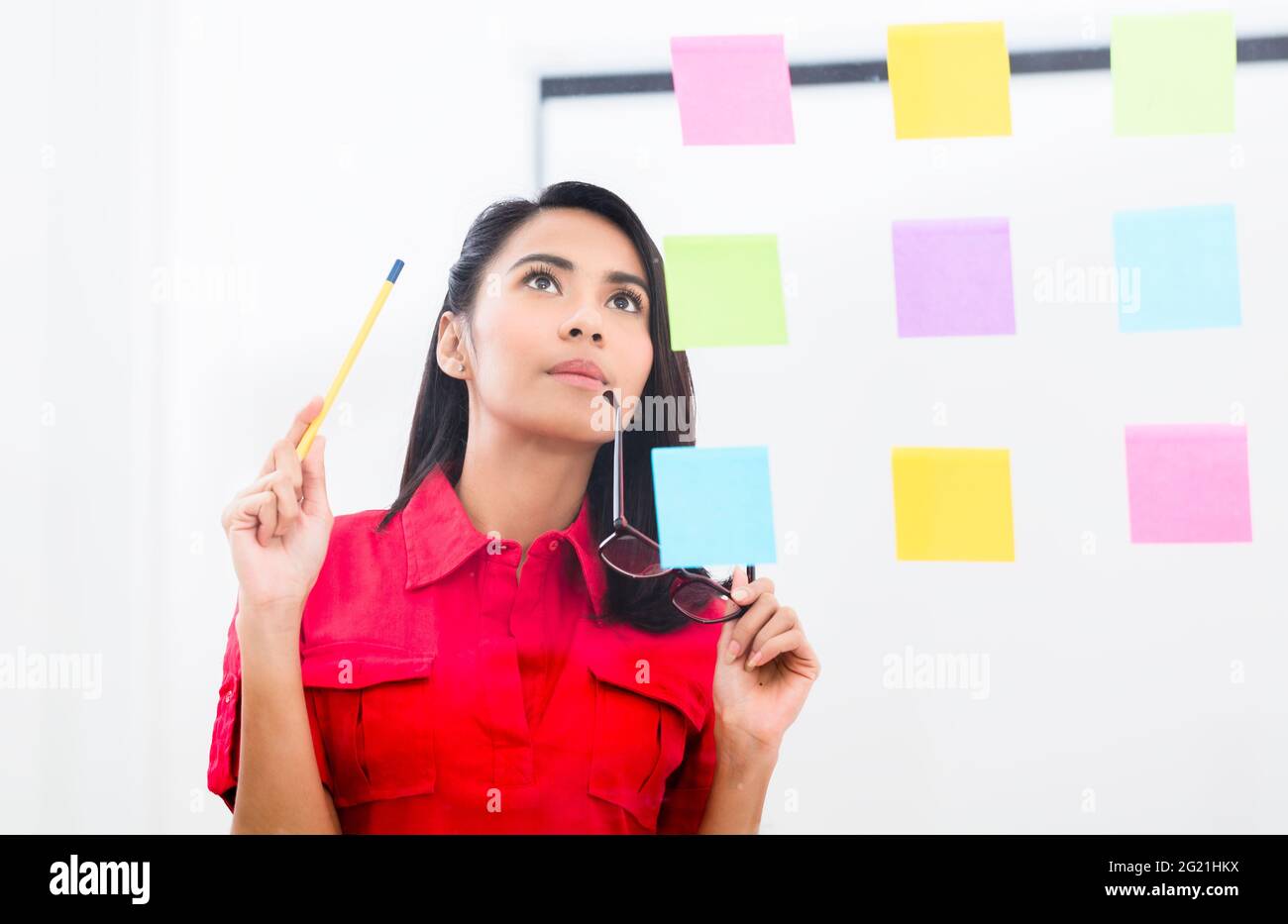 Portrait of young Asian employee looking at multiple reminders while ...