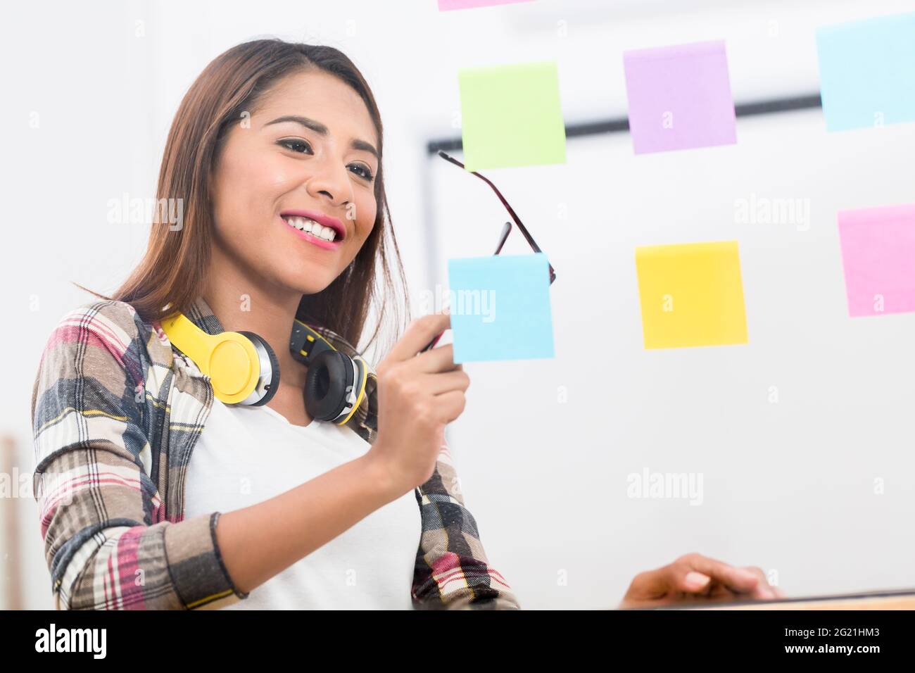 Portrait of young Asian employee looking at multiple reminders while ...