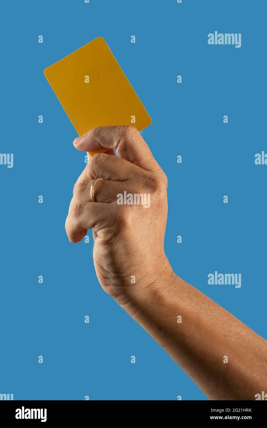 referee hand holding yellow punishment card on blue background Stock ...