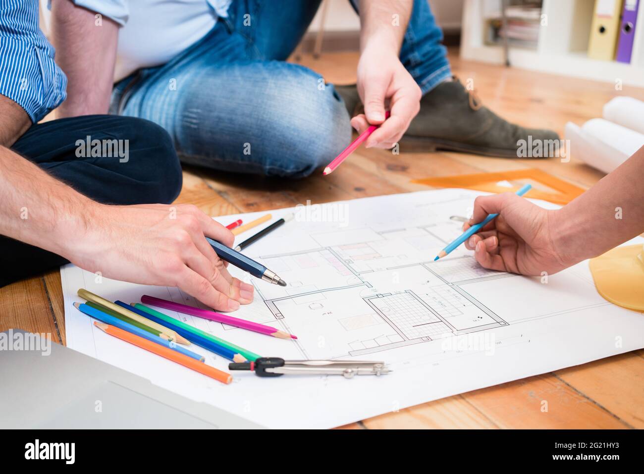 Team of architects and civil engineers sitting on floor with ...