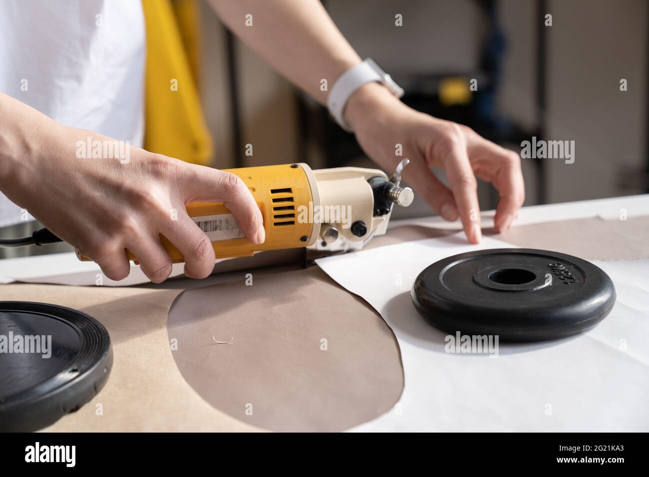 Closeup of woman tailor use electric cutting machine create patterns ...