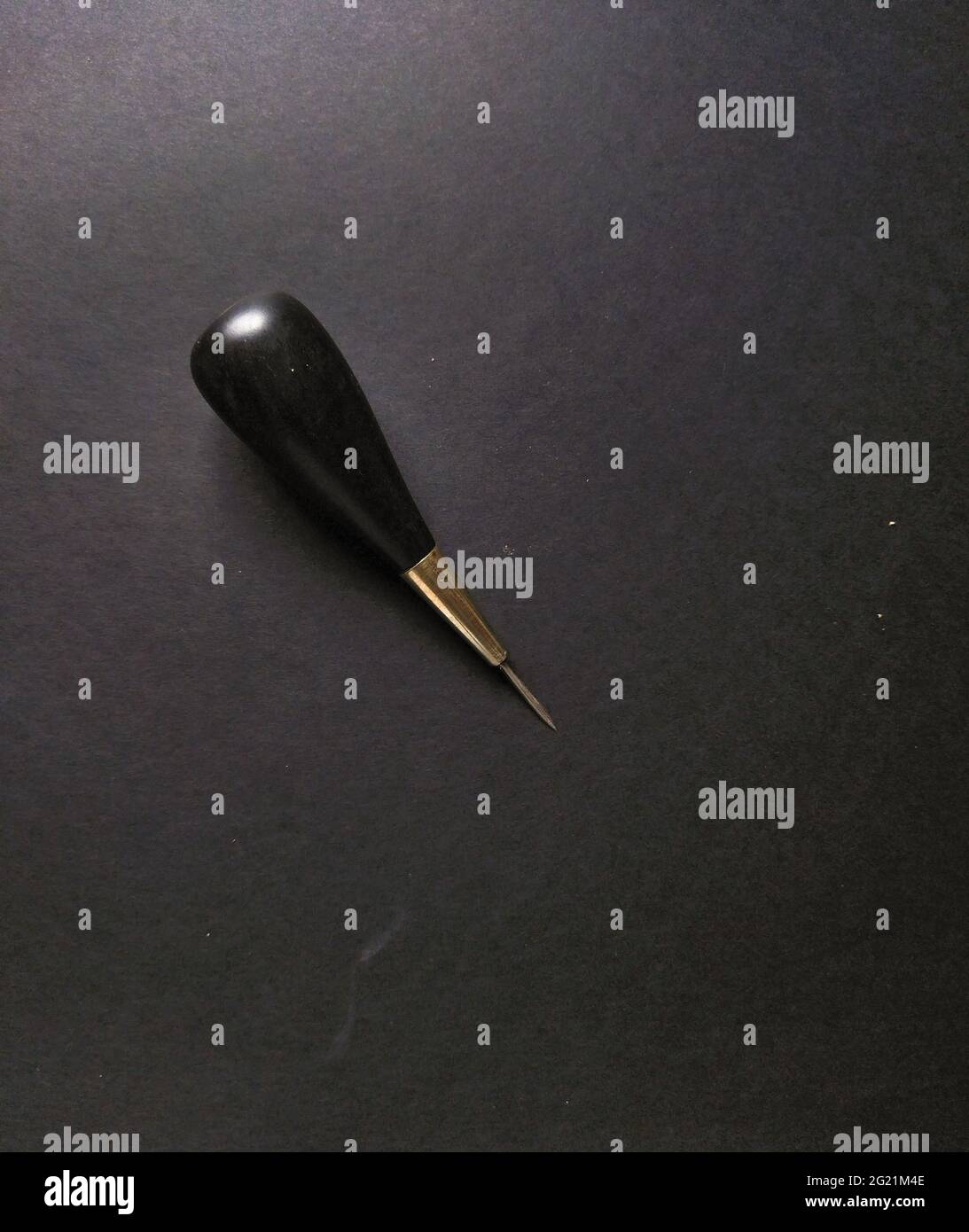 Vertical top view of an awl handle on a black surface Stock Photo - Alamy