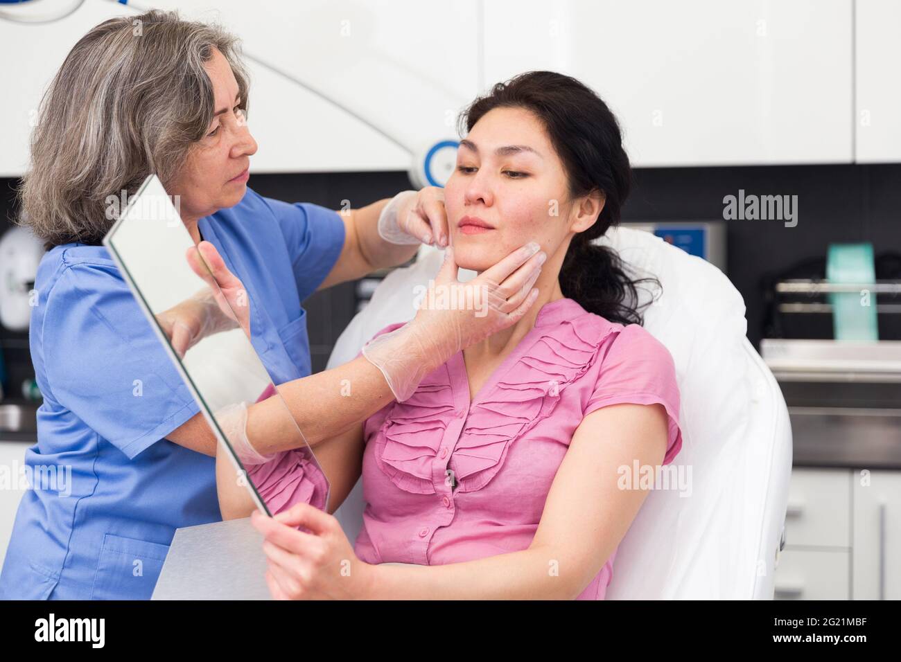 Experienced cosmetology doctor examines a young woman patient before ...