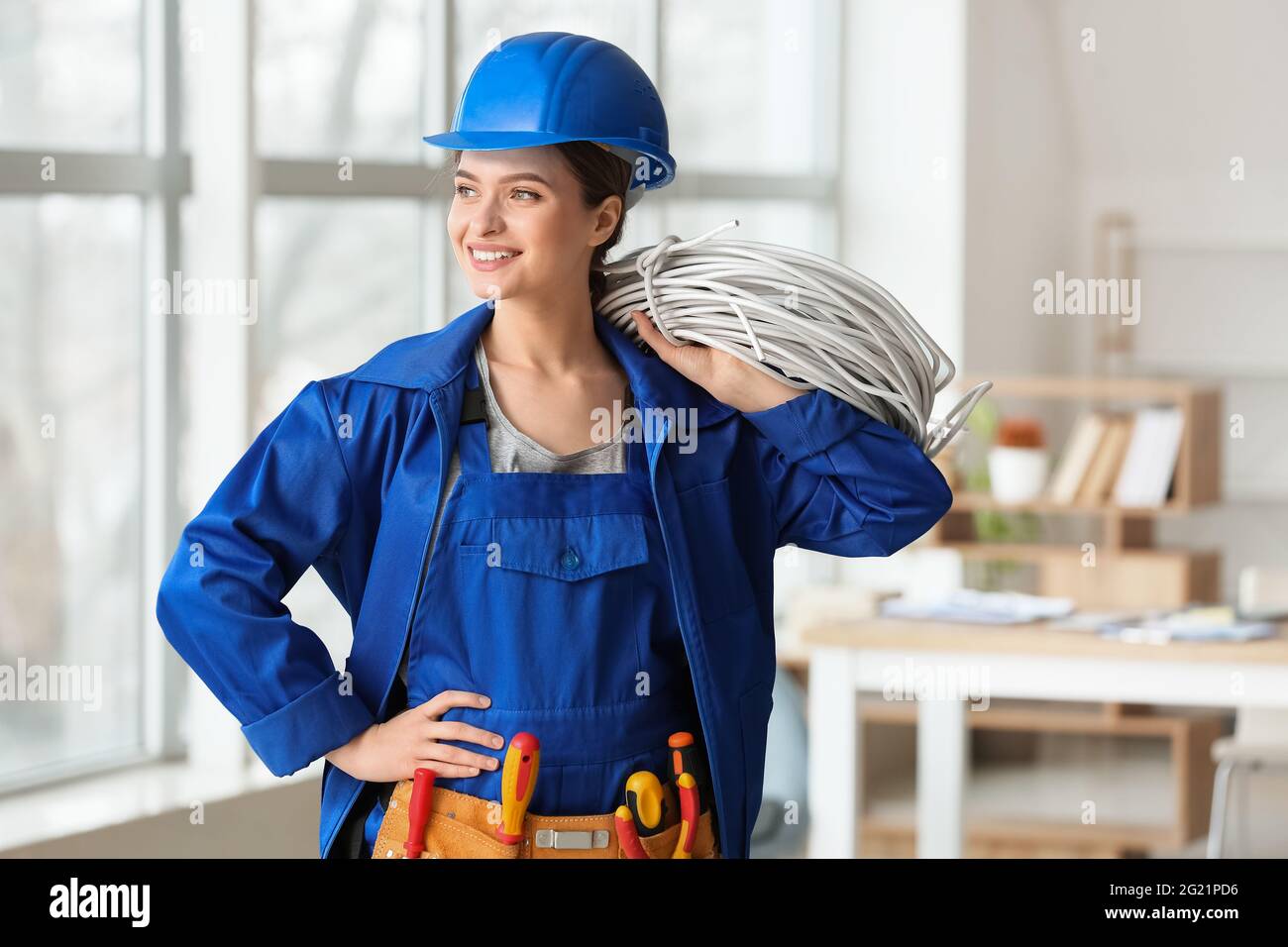 Beautiful female electrician with cables in room Stock Photo - Alamy