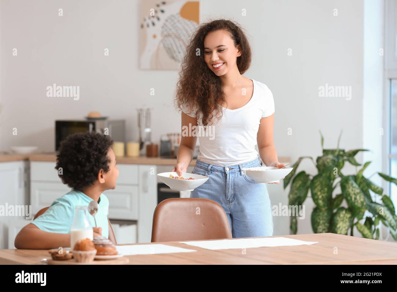 Little boy with mother eating cornflakes at home Stock Photo - Alamy