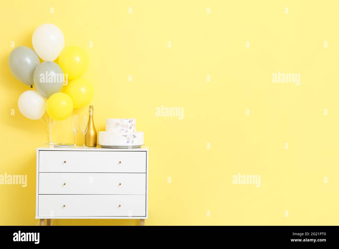 Birthday cake with champagne on chest of drawers and air balloons near ...