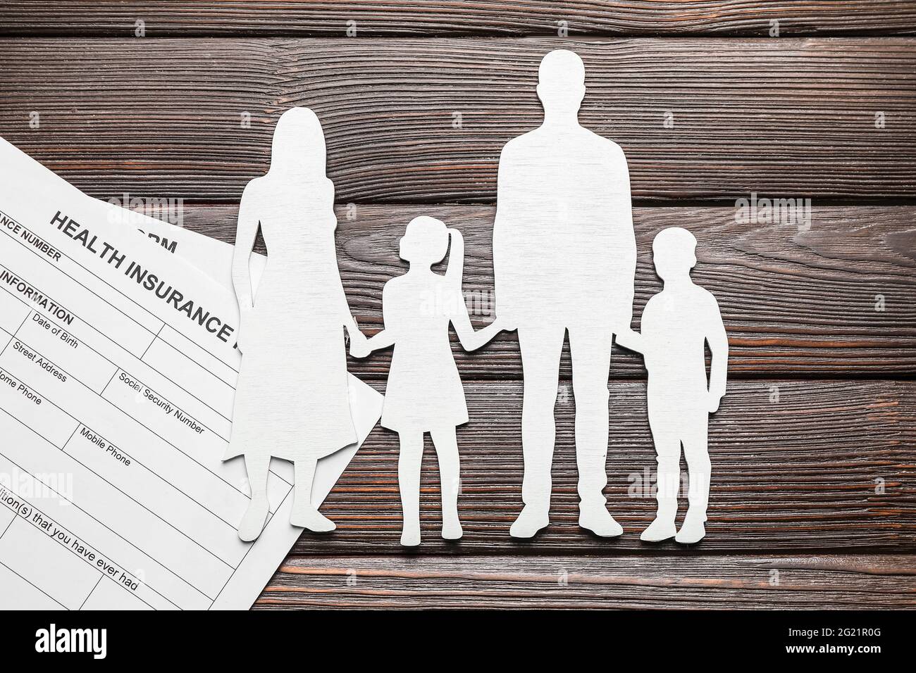 Family figures and health insurance form on dark wooden background ...