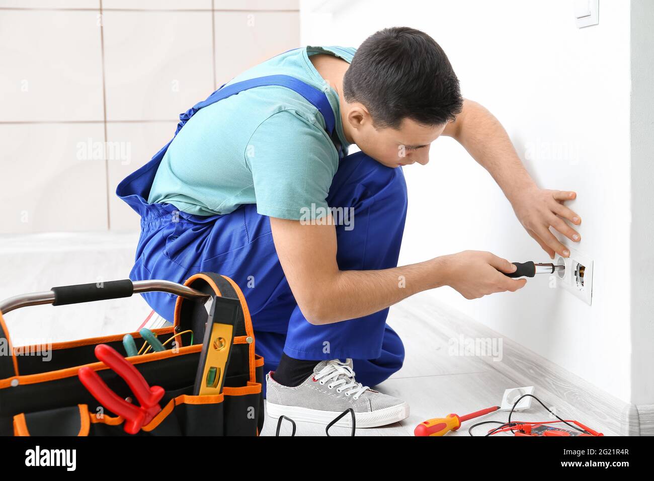 Young electrician repairing socket in room Stock Photo - Alamy