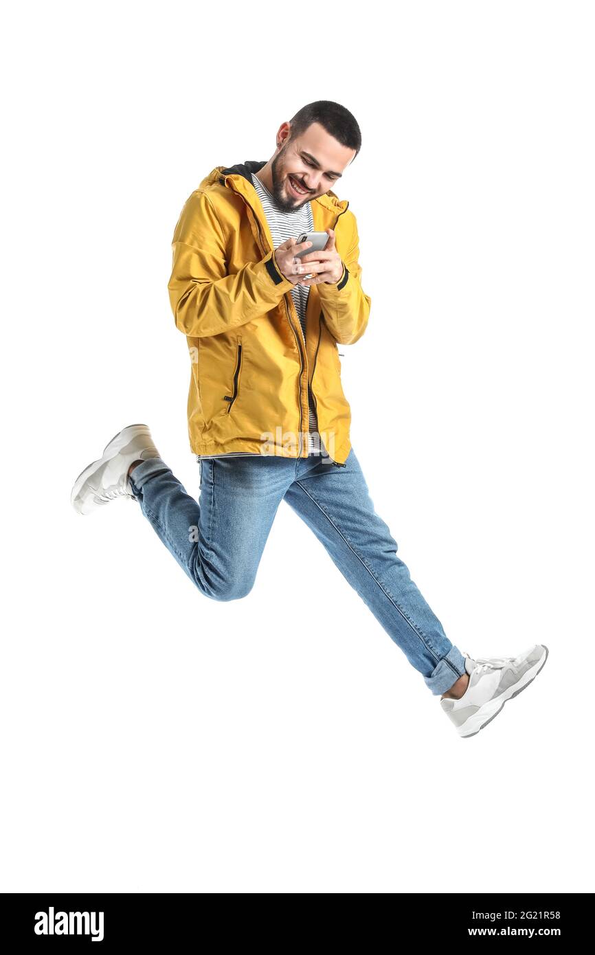 Jumping young man with mobile phone on white background Stock Photo - Alamy