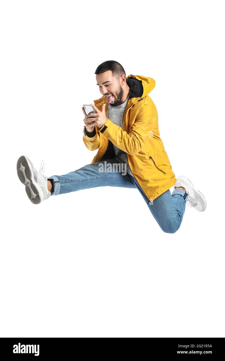 Jumping young man with mobile phone on white background Stock Photo - Alamy