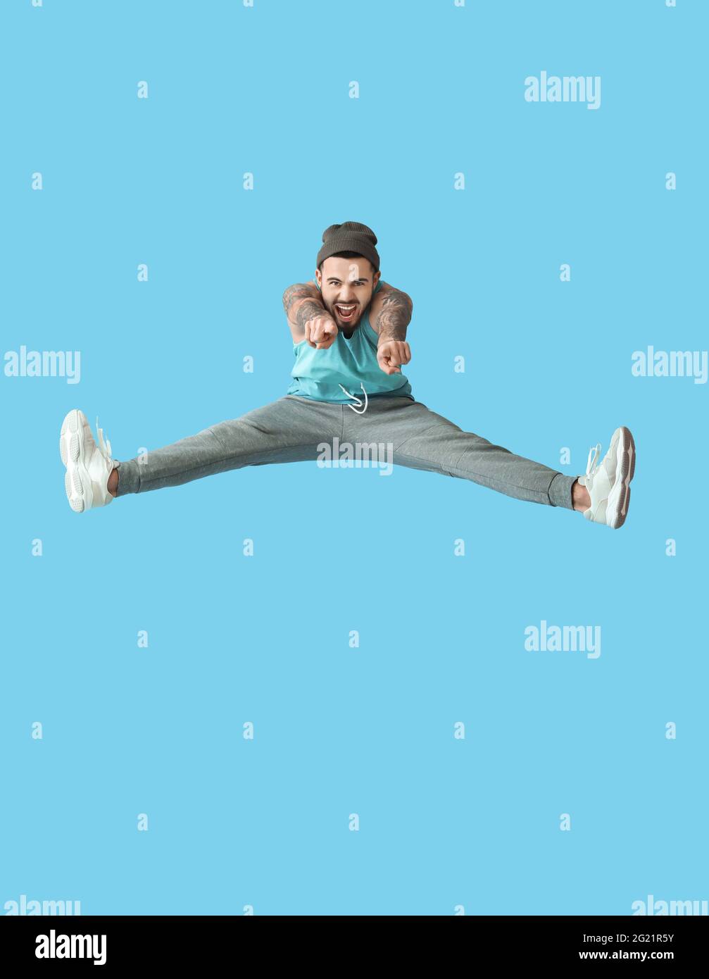 Jumping young man pointing at viewer on color background Stock Photo ...