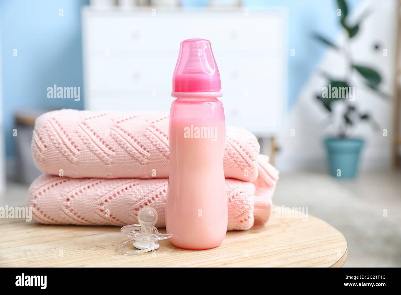 Bottle of milk for baby with pacifier and clothes on table Stock Photo ...