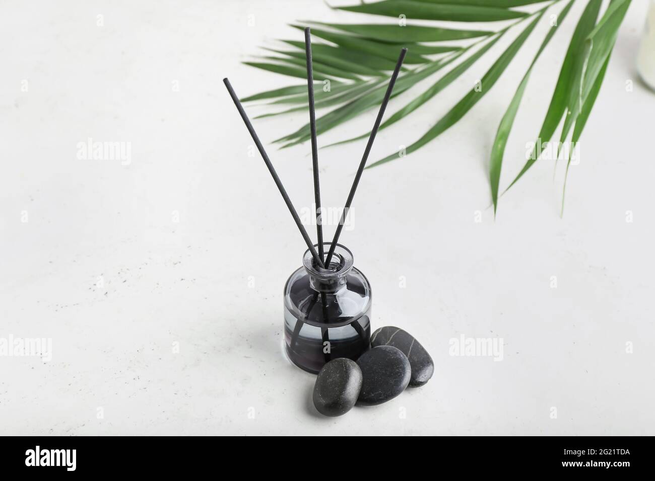 Reed diffuser with tropical leaf and spa stones on white background ...