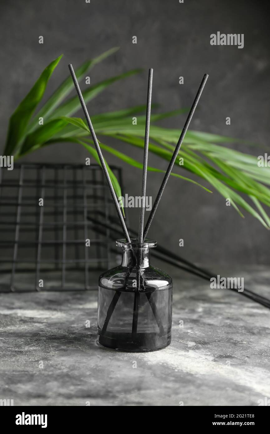 Reed diffuser with tropical leaf on dark background Stock Photo - Alamy