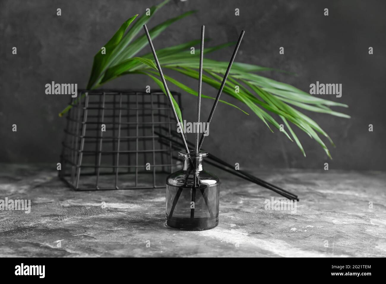 Reed diffuser with tropical leaf on dark background Stock Photo - Alamy
