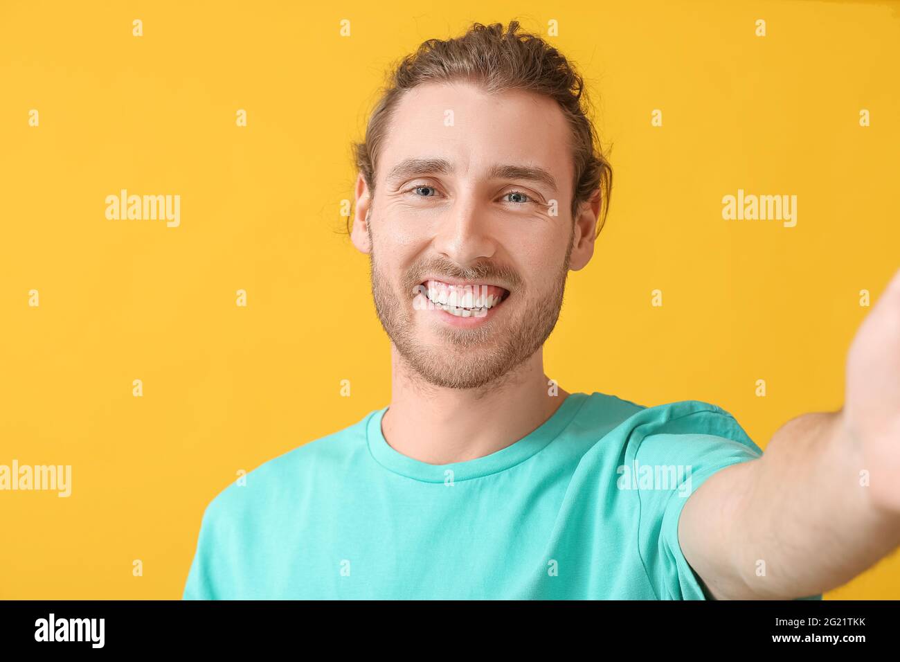 Smiling young man taking selfie on color background Stock Photo - Alamy