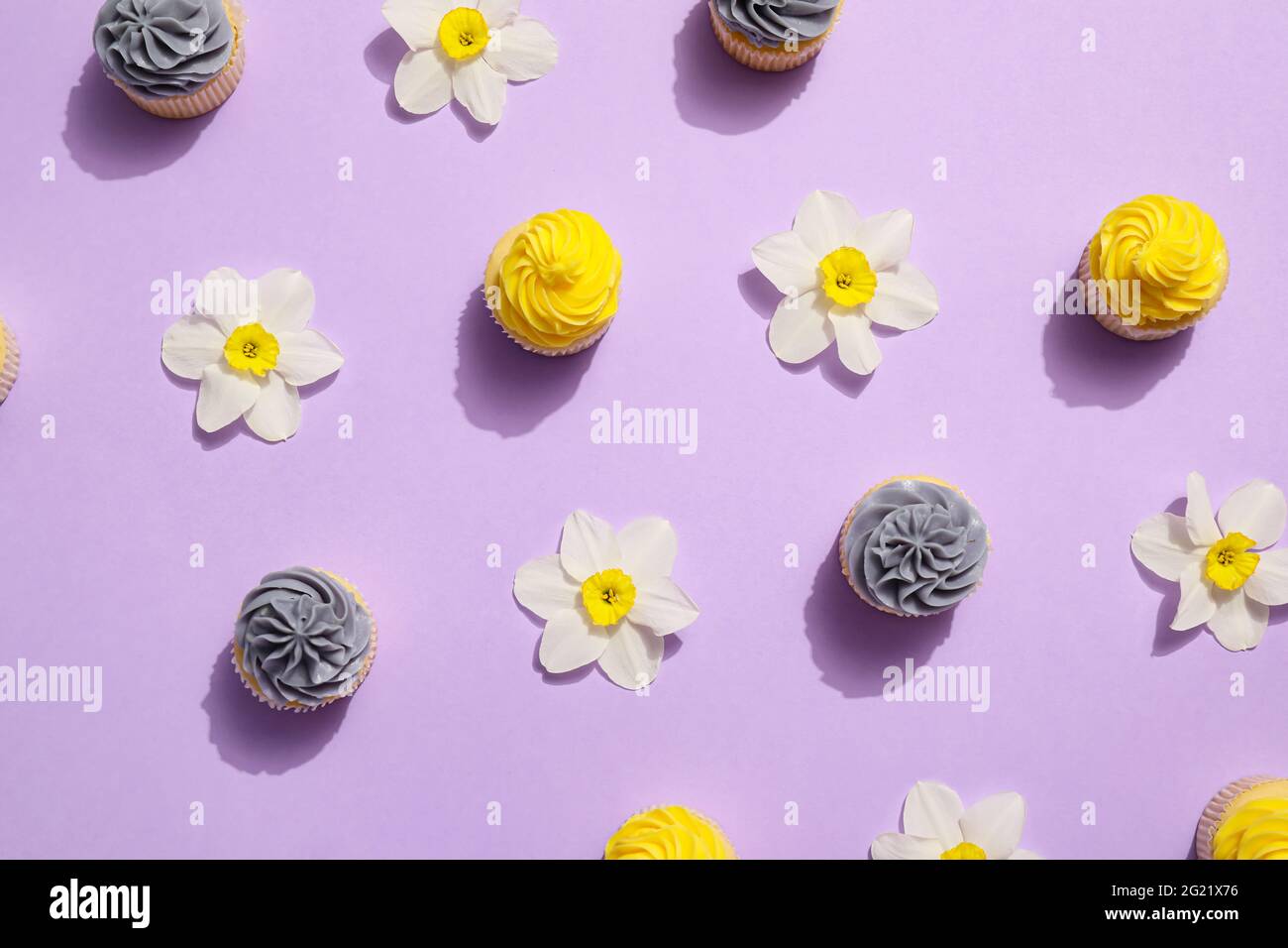 Tasty cupcakes with beautiful narcissus flowers on color background ...