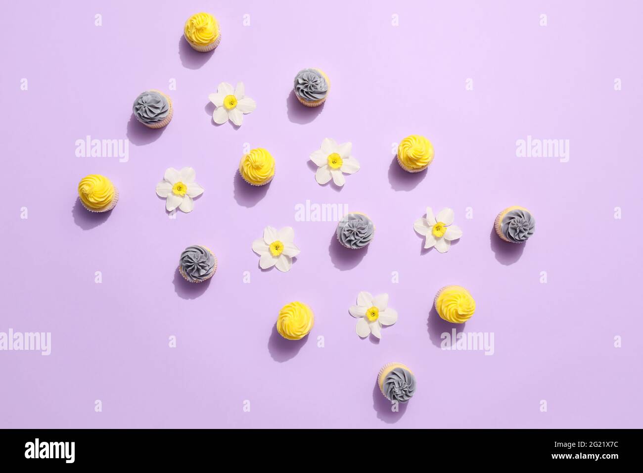 Tasty cupcakes with beautiful narcissus flowers on color background ...