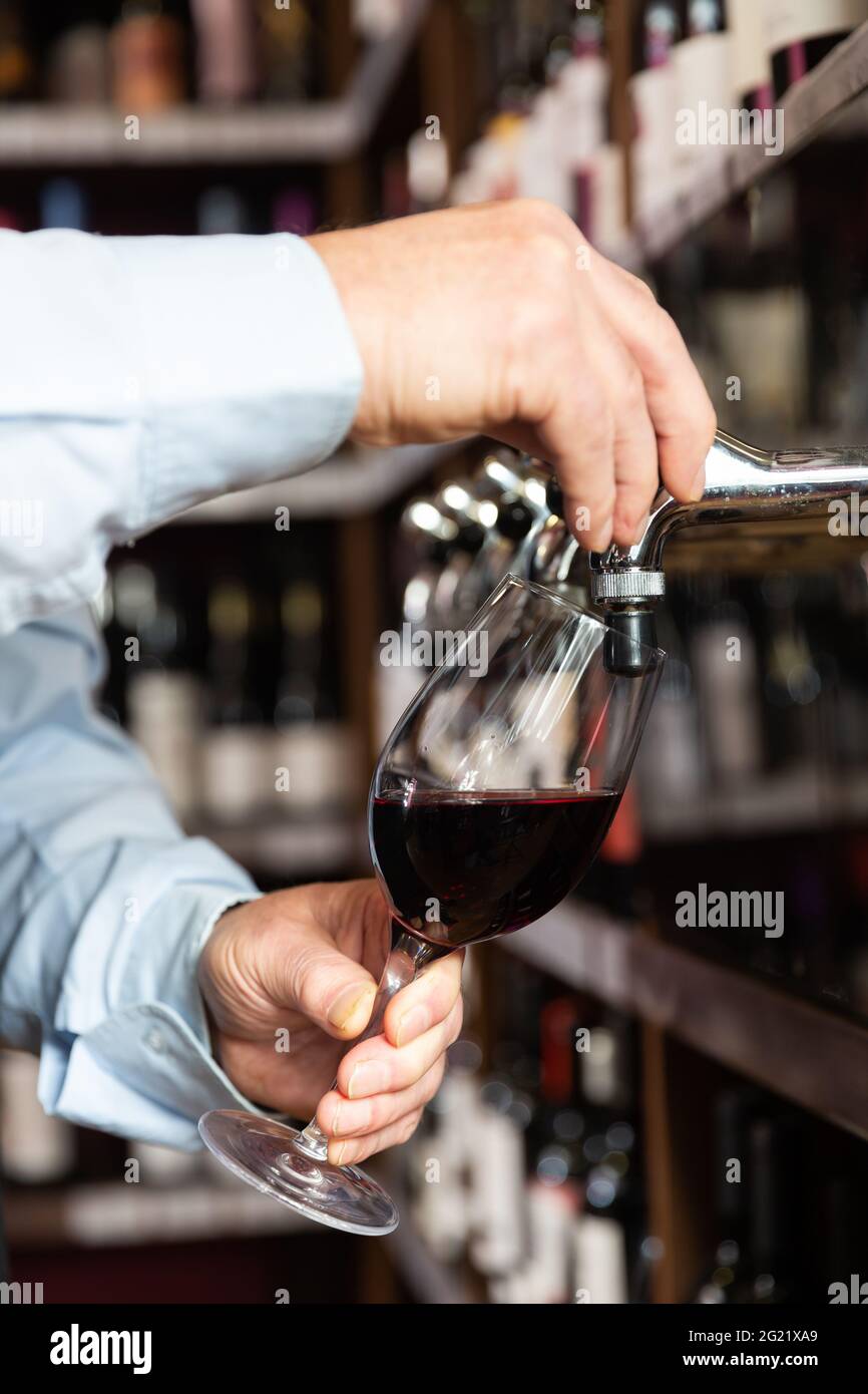 Bartender hand pouring draught red wine to glass Stock Photo - Alamy
