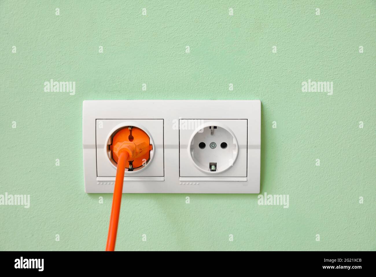 Electric socket with plug on color wall Stock Photo - Alamy