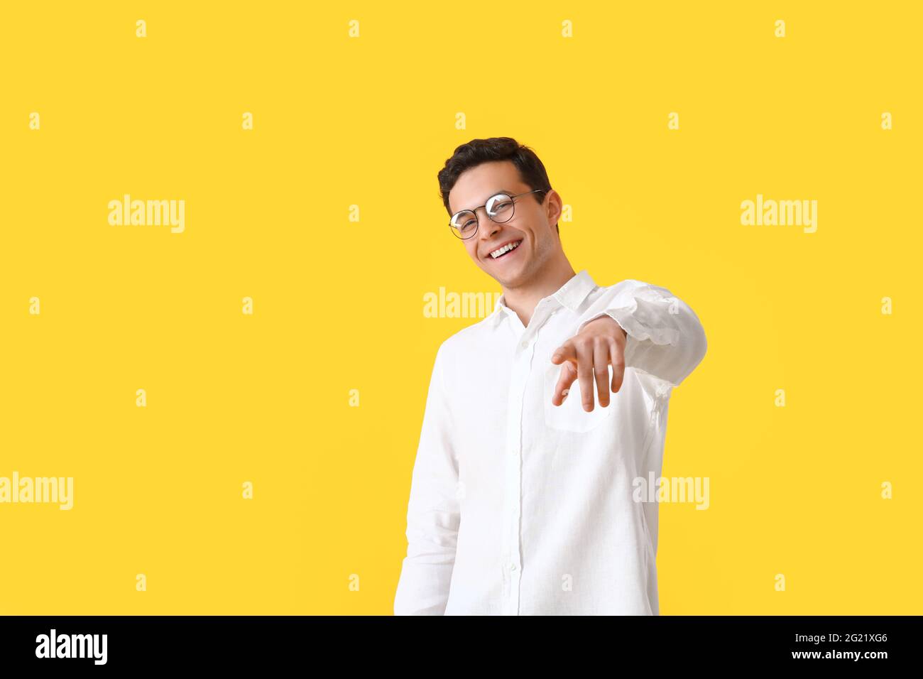 Handsome young man pointing at viewer on yellow background Stock Photo ...
