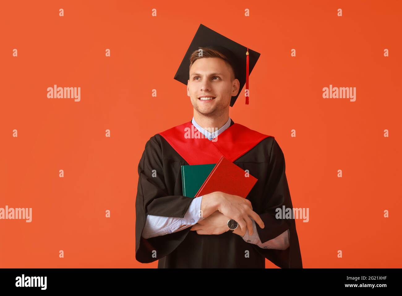 Male graduating student with books on color background Stock Photo - Alamy